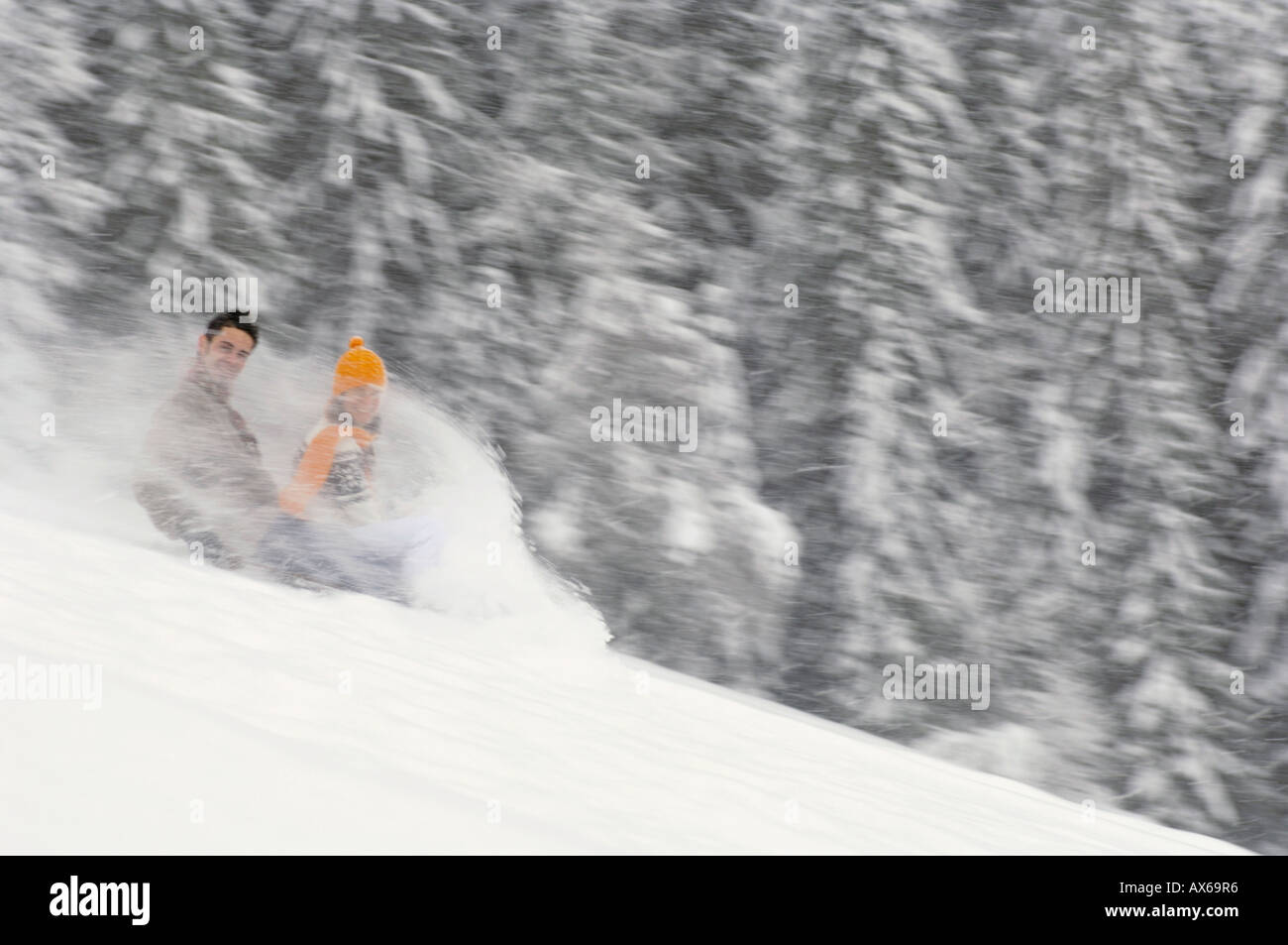 Young couple sliding on sledge, side view Stock Photo - Alamy