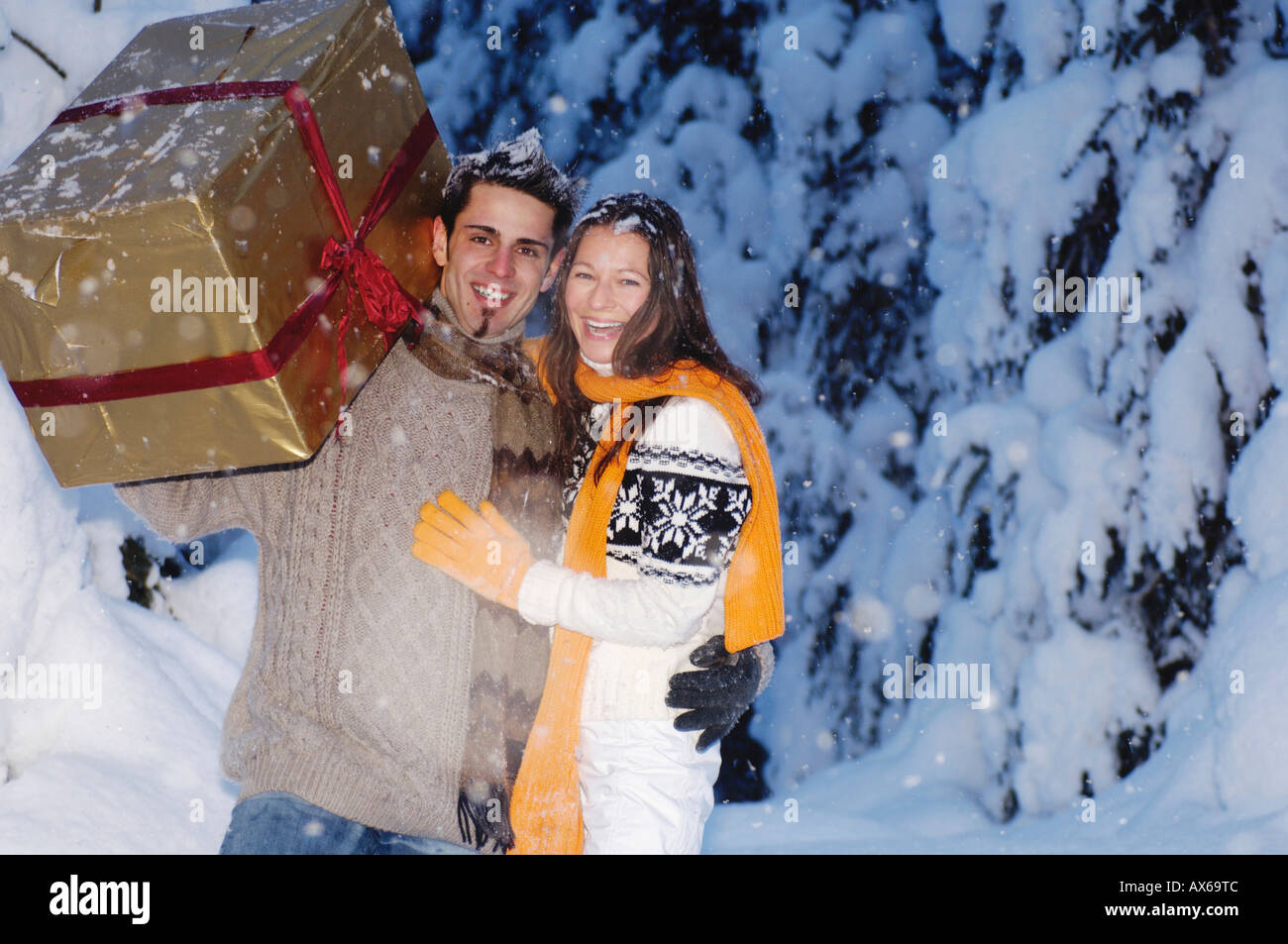 Man pulling woman holding present on sledge, side view Stock Photo - Alamy