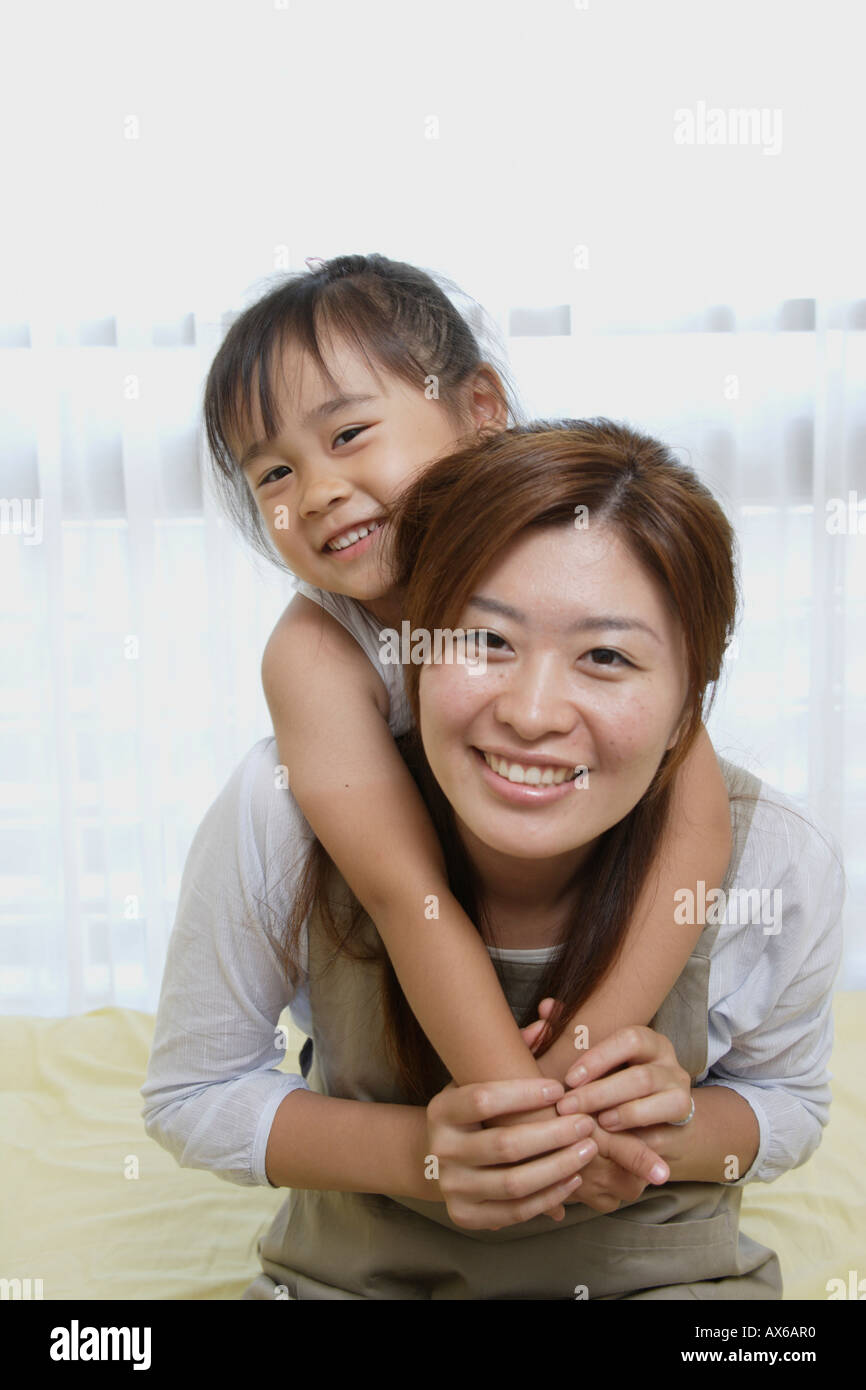 A mother carrying her daughter on her back Stock Photo - Alamy