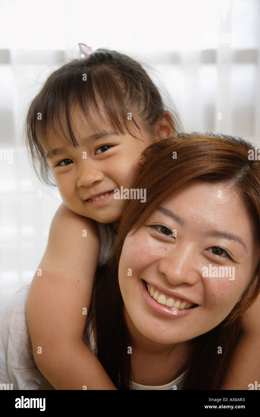 A mother carrying her daughter on her back Stock Photo - Alamy