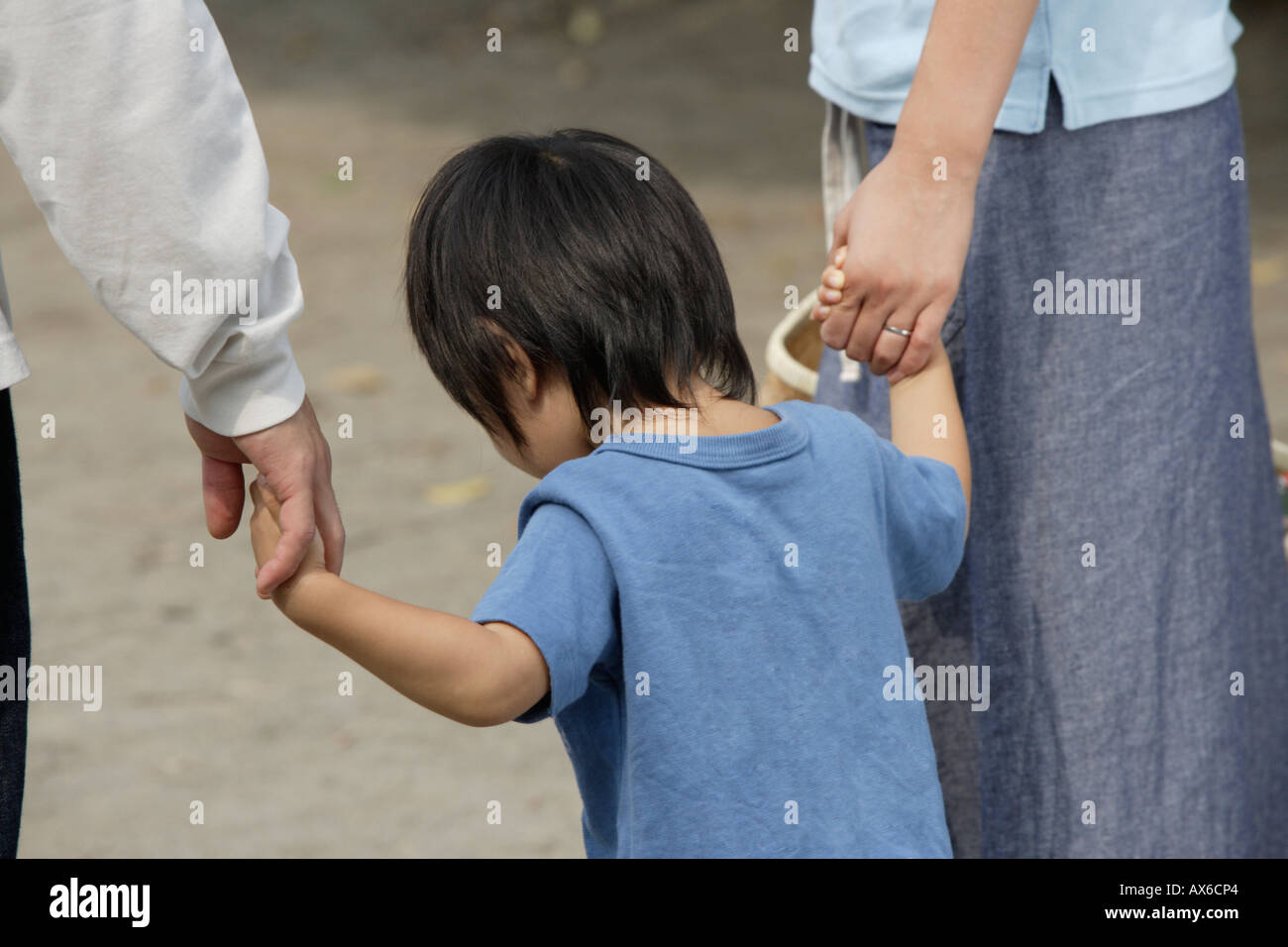 A boy standing between mother and father Stock Photo - Alamy