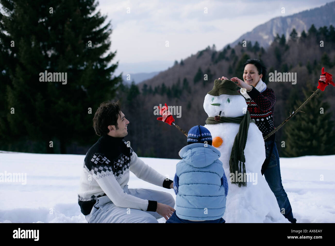 Family making a snowman Stock Photo - Alamy