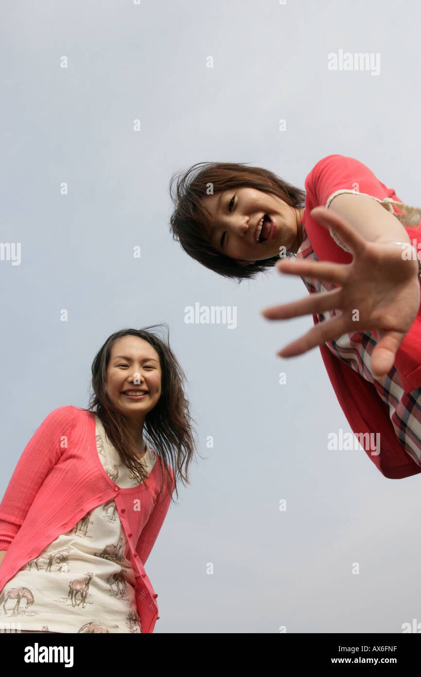 Low angle view of two young women showing their palms over the camera ...