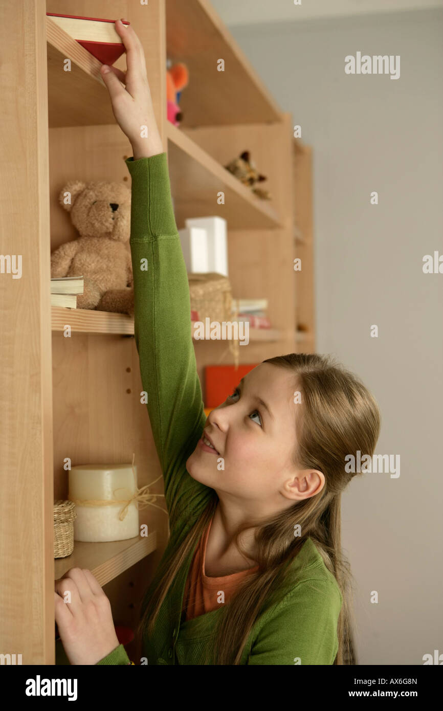 Girl snatching at a book in a shelf Stock Photo - Alamy