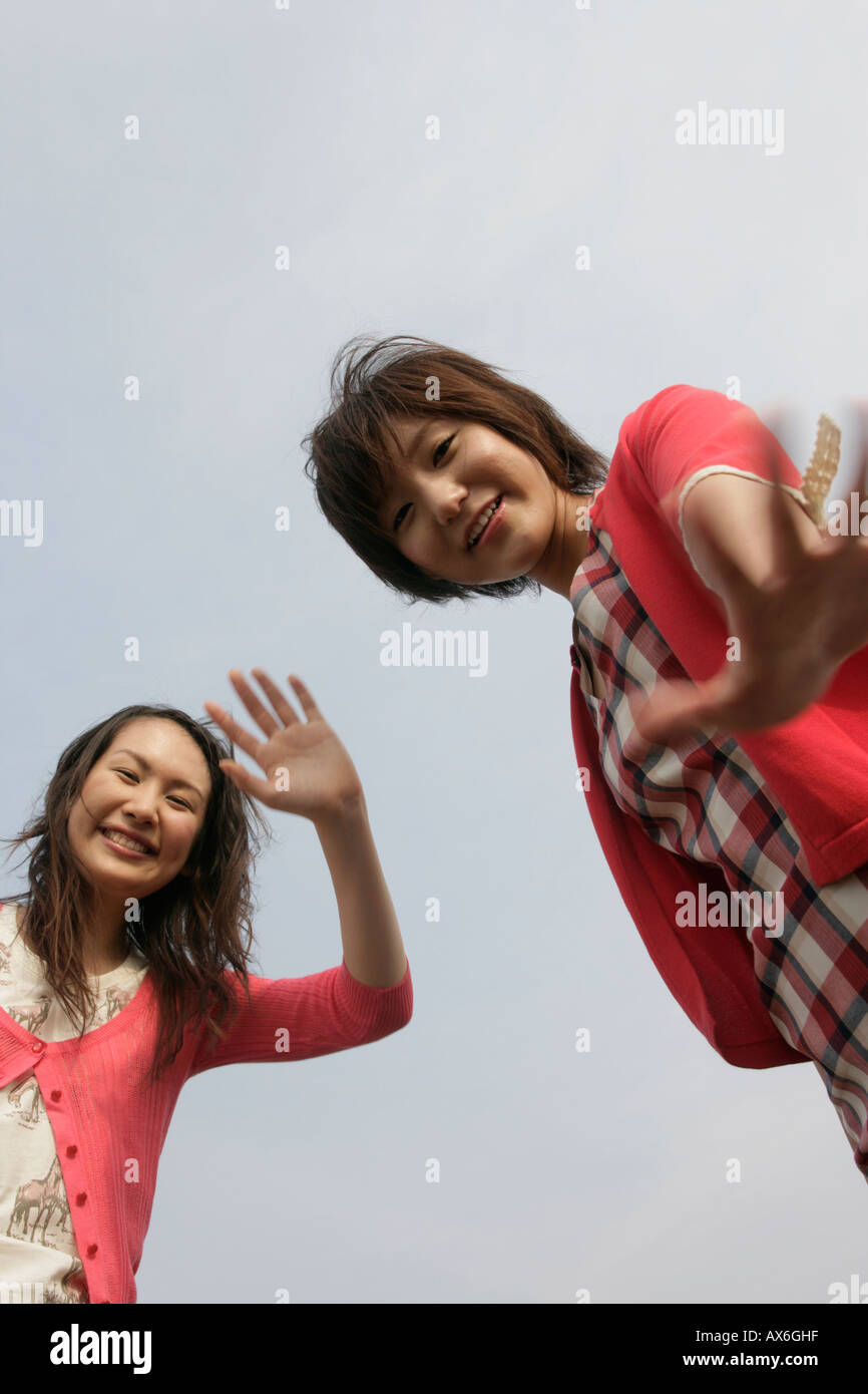 Low angle view of two young women showing their palms over the camera ...