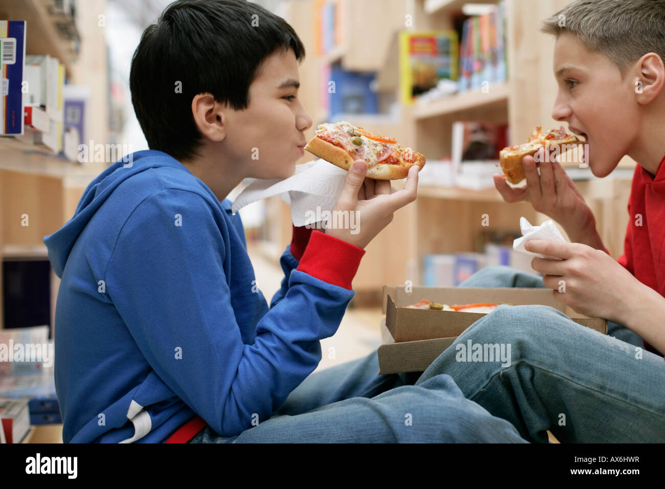 Two boys eating pizza inside a library, fully released Stock Photo - Alamy