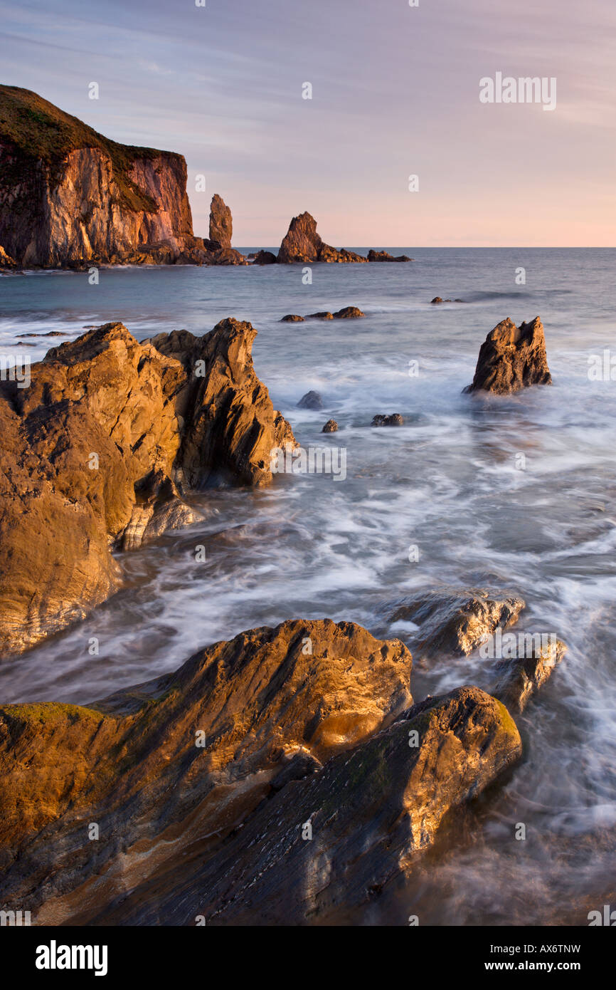 Golden evening sunlight catches the rocky coast of Bantham in South ...