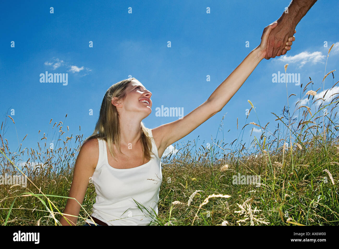 Woman in field being helped up Stock Photo - Alamy