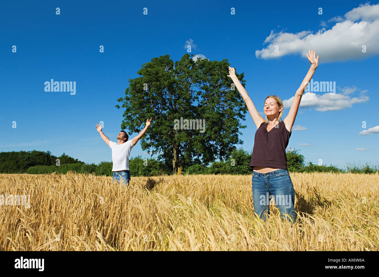 Couple in field with arms outstretched Stock Photo - Alamy