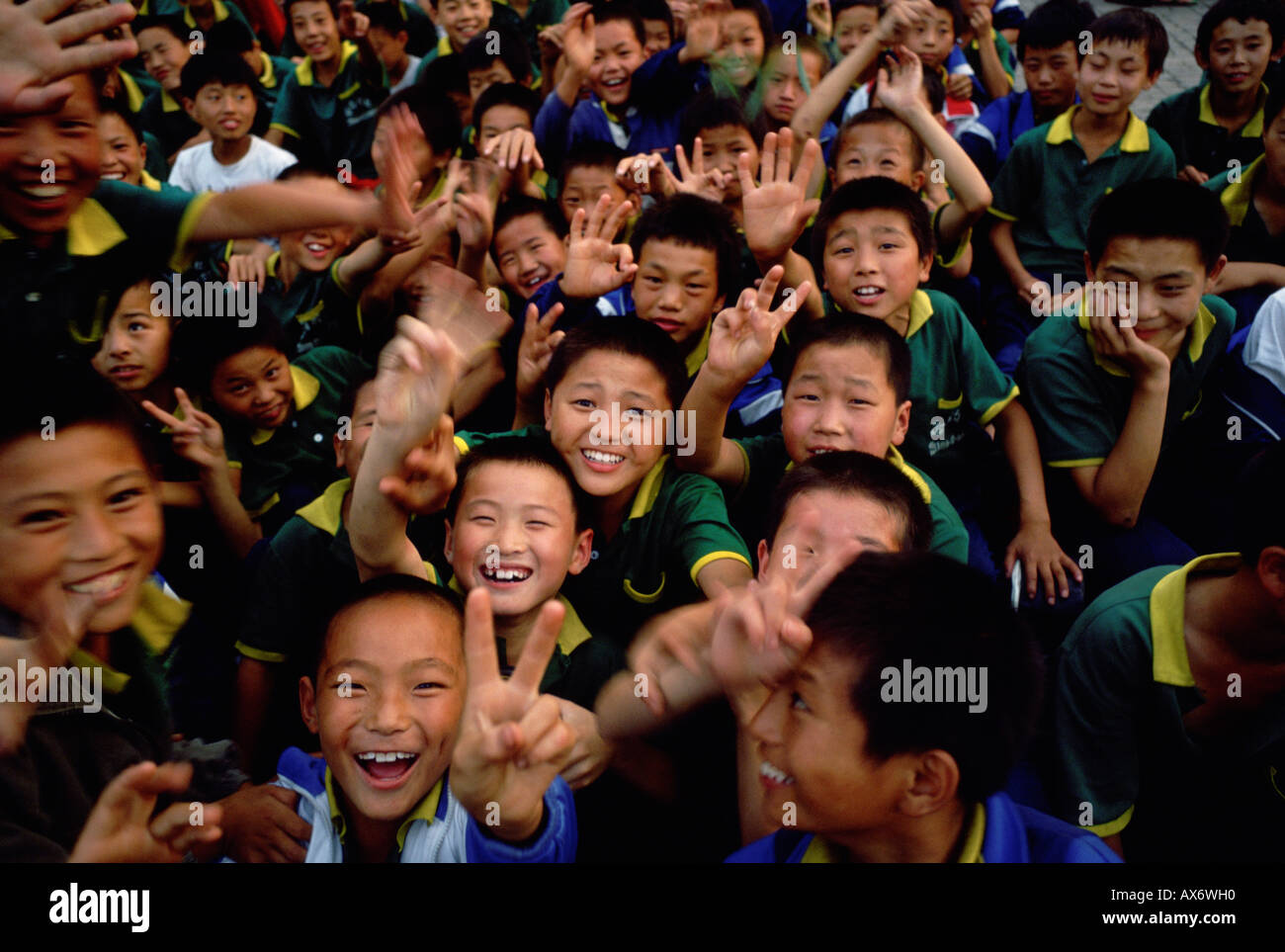A crowd of Chinese children wave to the camera in a fit of excitement ...