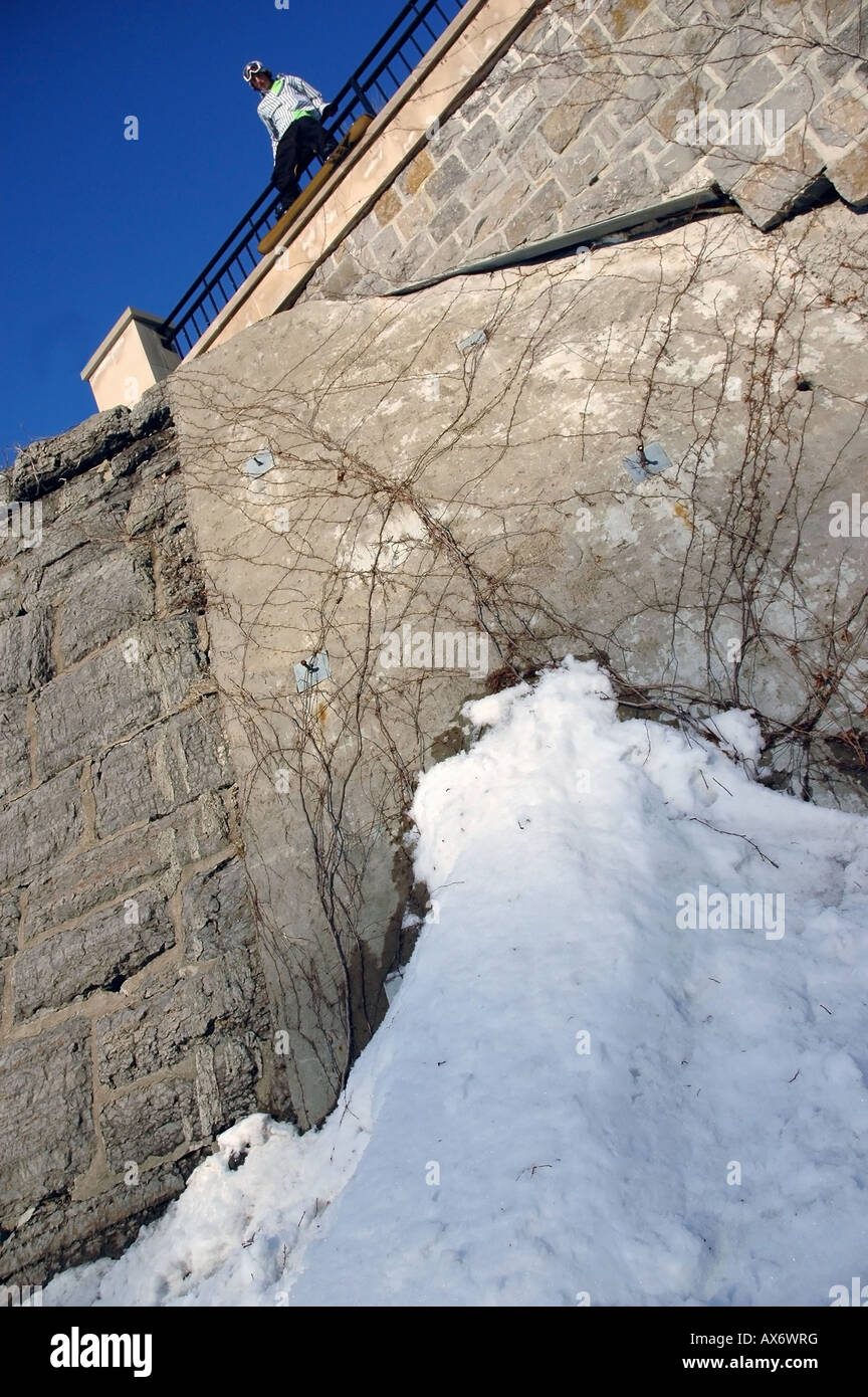 A snowboarder sets up for a risky jump off an extremely high cliff ...
