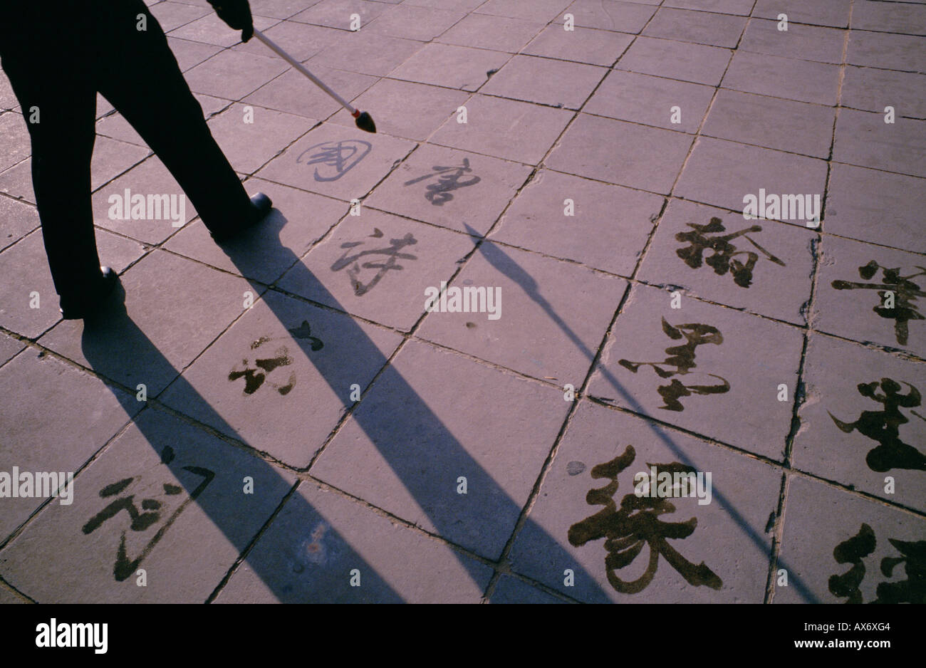 A man paints chinese characters and calligraphy in water in Beijing ...