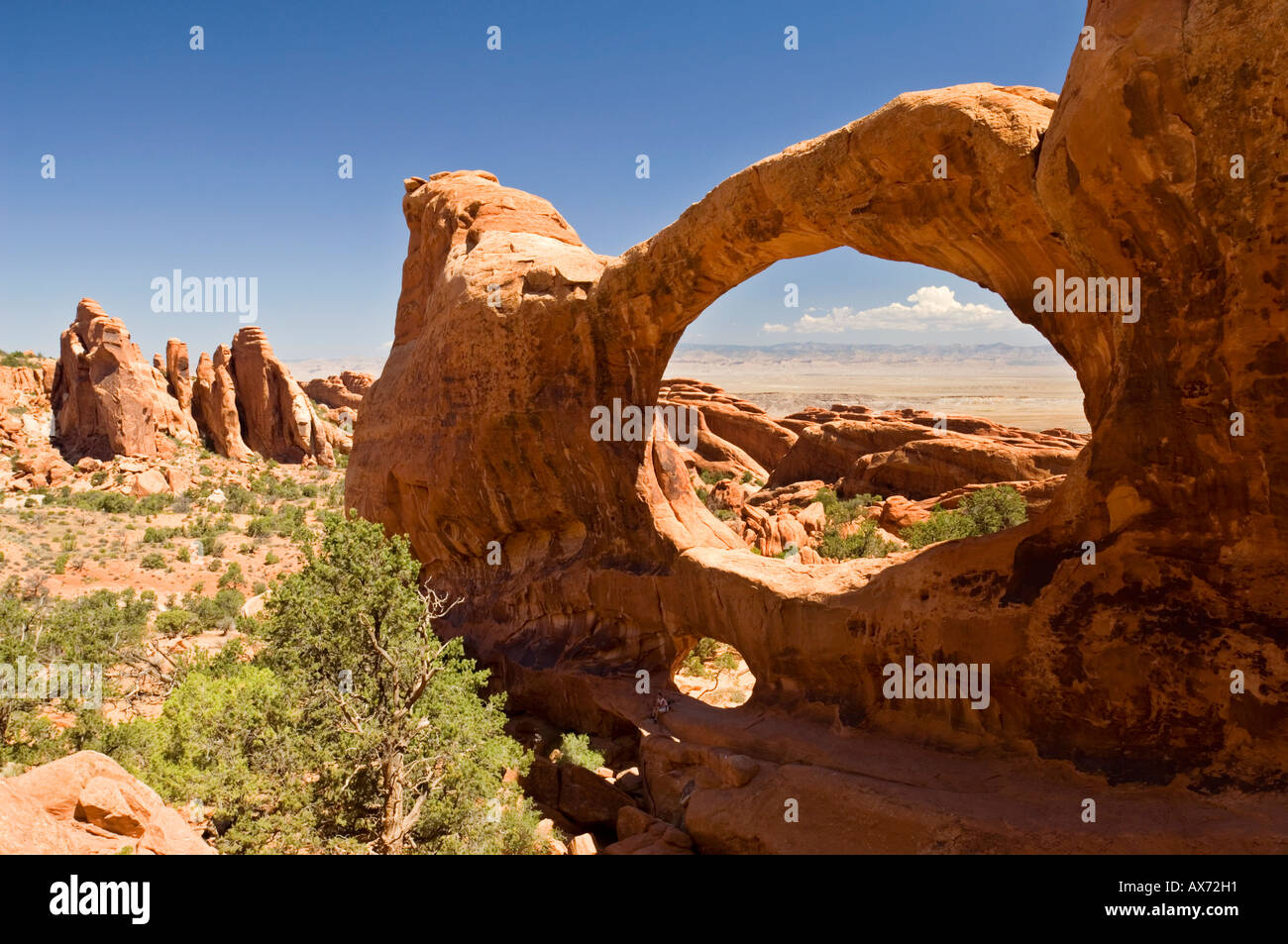 Lone hiker rests at the base of the Double O Arch, Devil's Garden Trail ...
