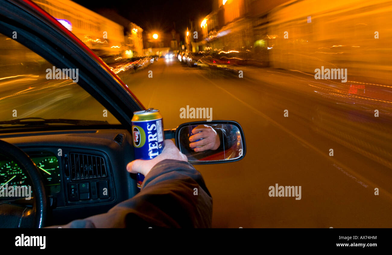 drink-driving, driving at night whilst holding a can of beer, showing ...