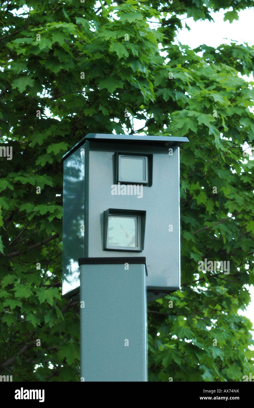 A traffic camera box setup next to a large tree to detect red light ...