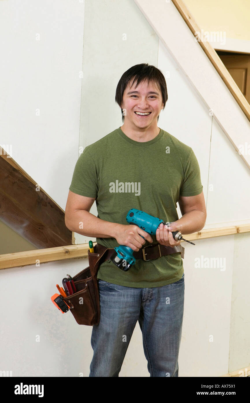Portrait of a young man holding a drill smiling Stock Photo - Alamy
