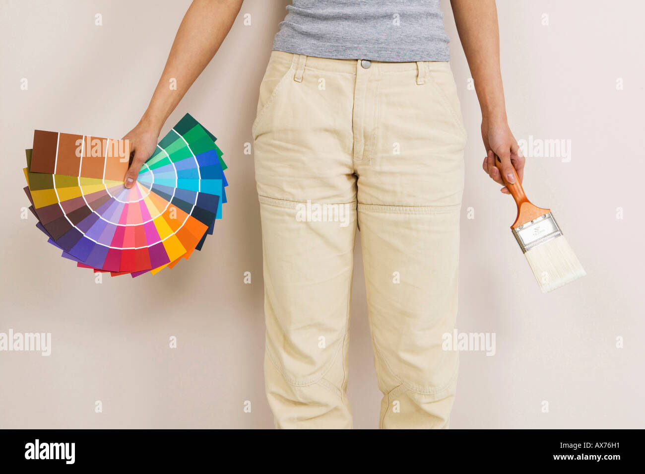 Mid section view of a woman holding color swatches and a paintbrush ...