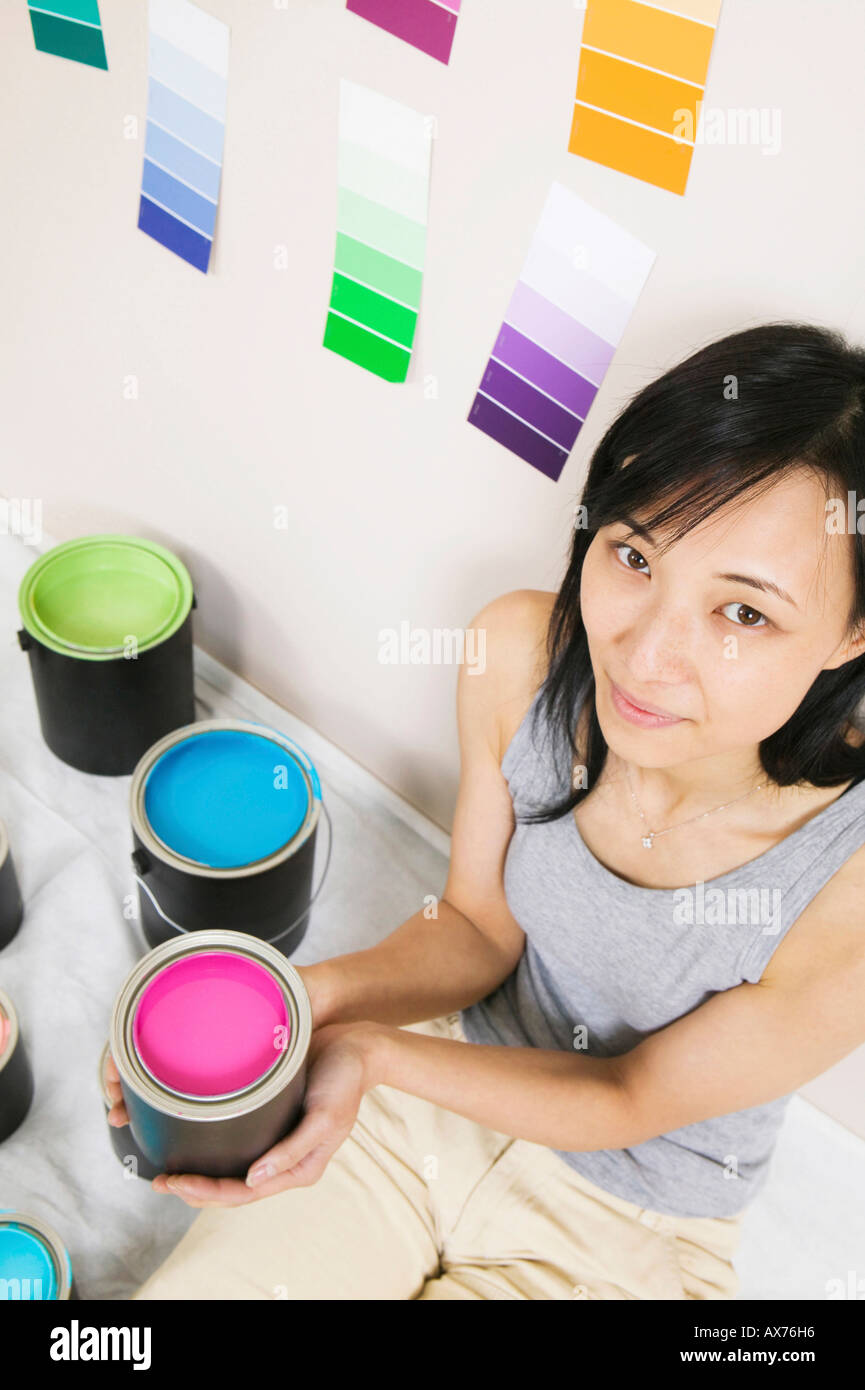 Portrait of a young woman holding a paint can with color swatches on a ...
