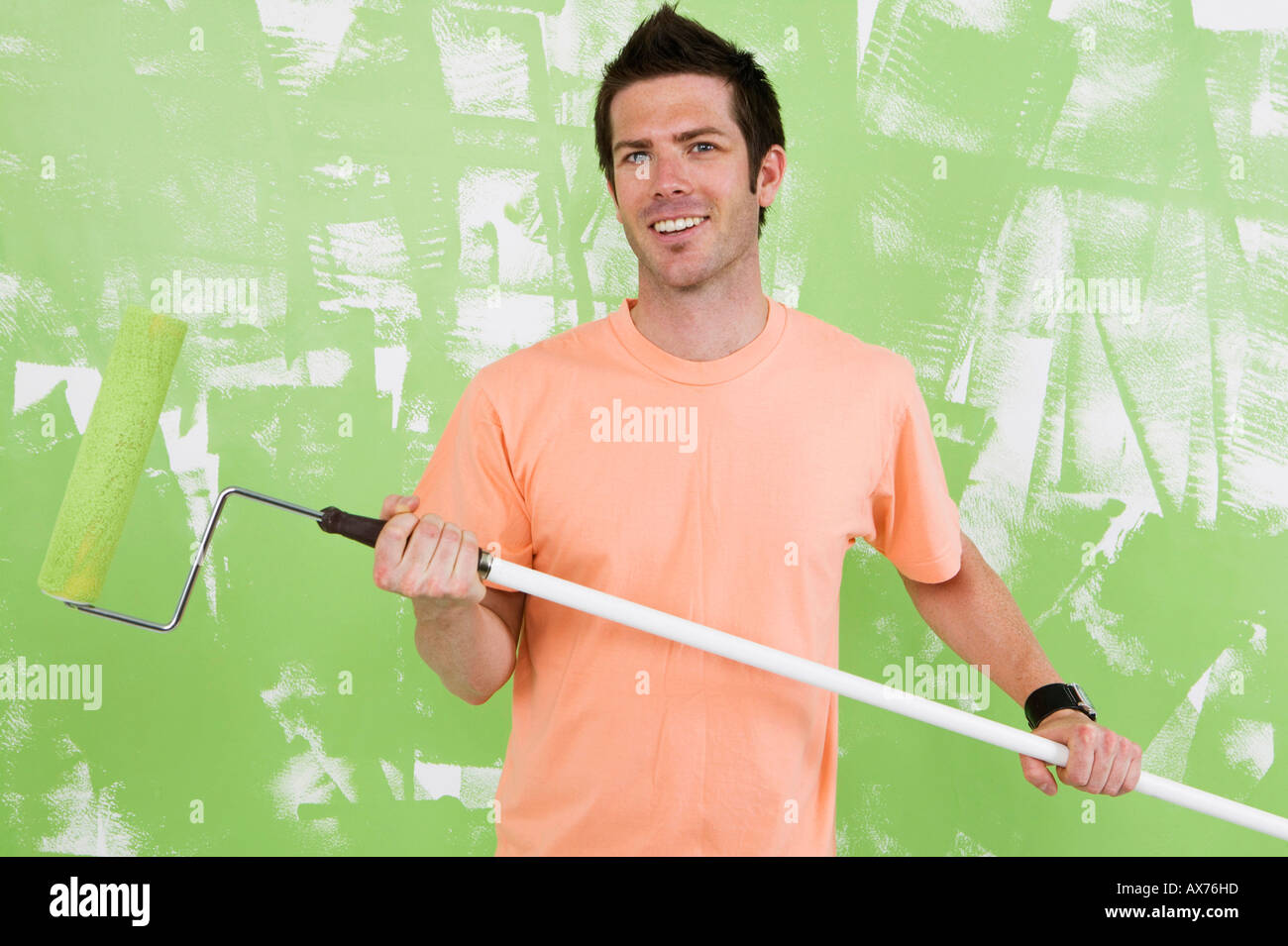 Portrait of a young man holding a paint roller Stock Photo - Alamy