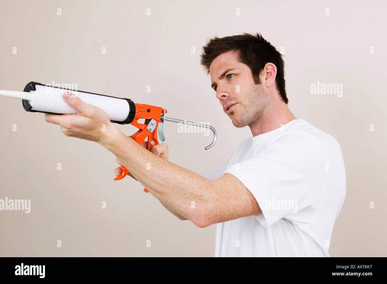 Side profile of a young man holding a caulk gun Stock Photo - Alamy