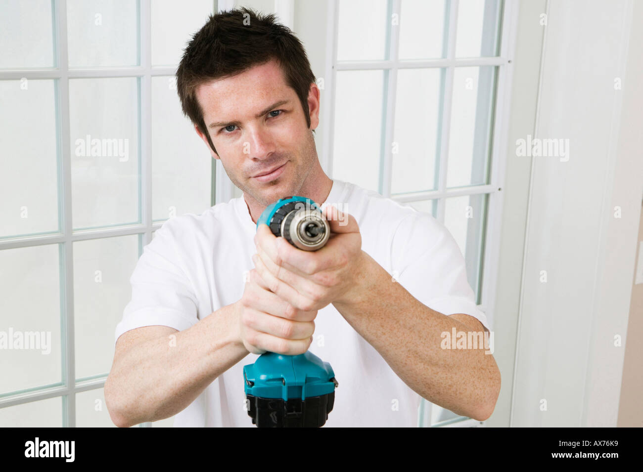 Portrait of a young man holding a drill Stock Photo - Alamy