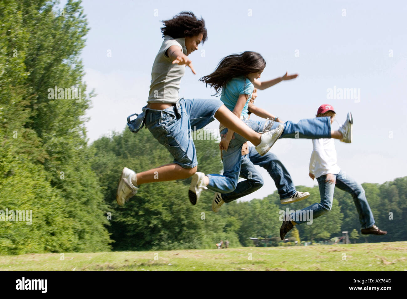 Side profile of four children jumping in a park Stock Photo - Alamy