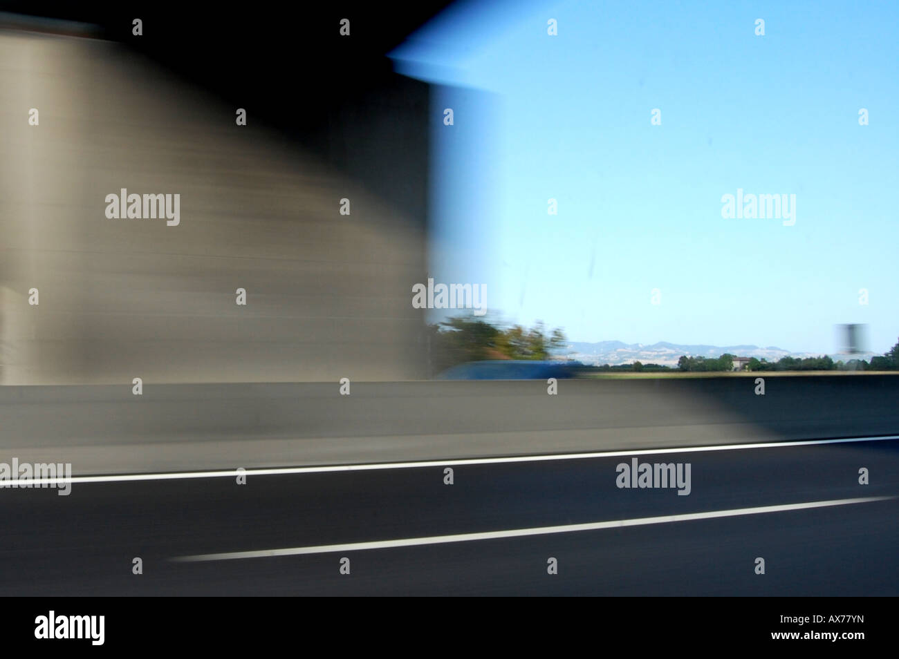 A photograph taken from a car window showing a blurred motorway and ...