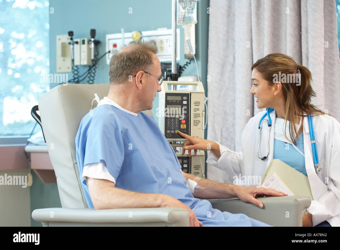 Female doctor operating an IV drip machine with a male patient looking ...