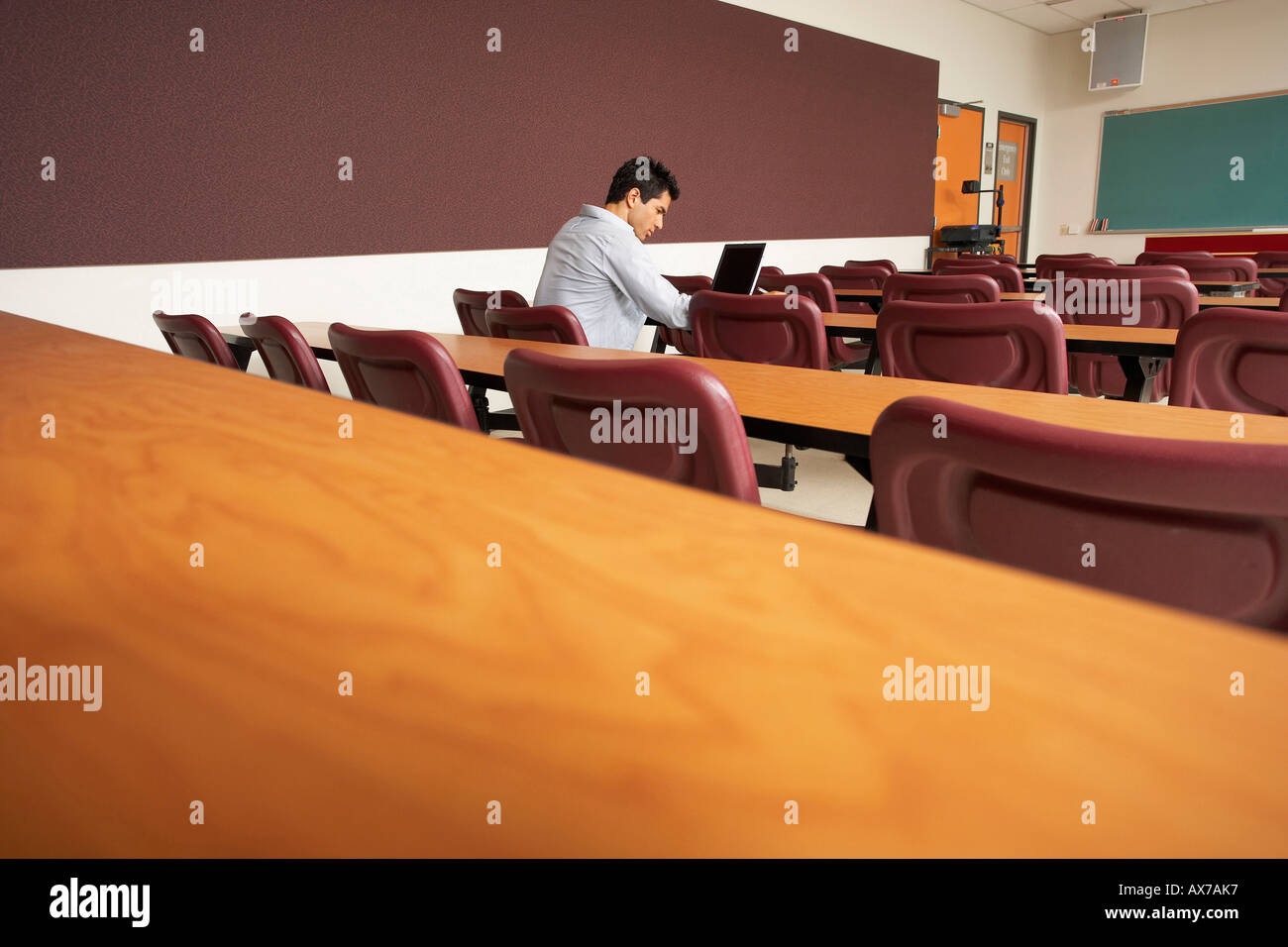 Side profile of a college student sitting in a lecture hall and using a ...