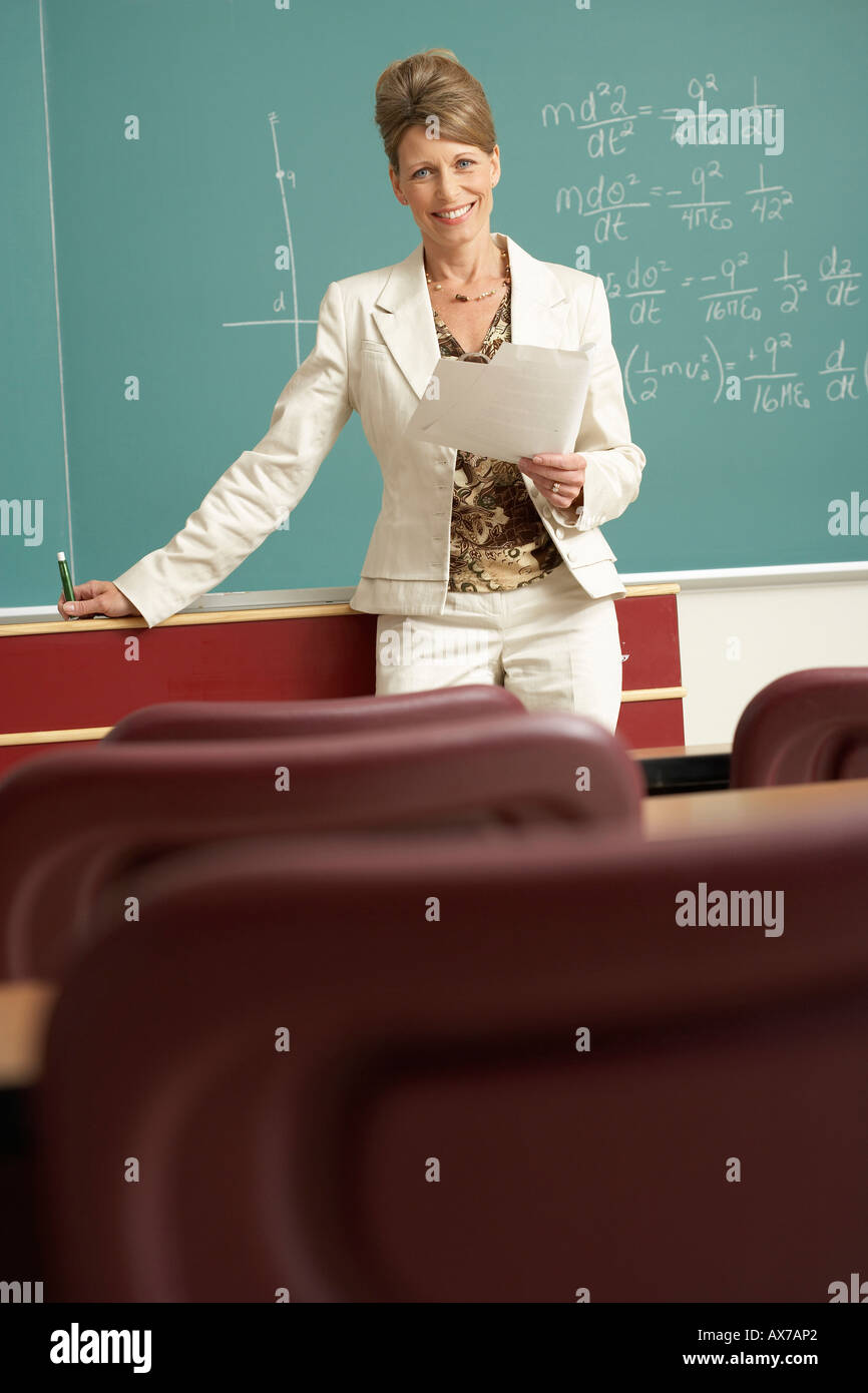 Female professor standing in front of a blackboard and holding a paper ...