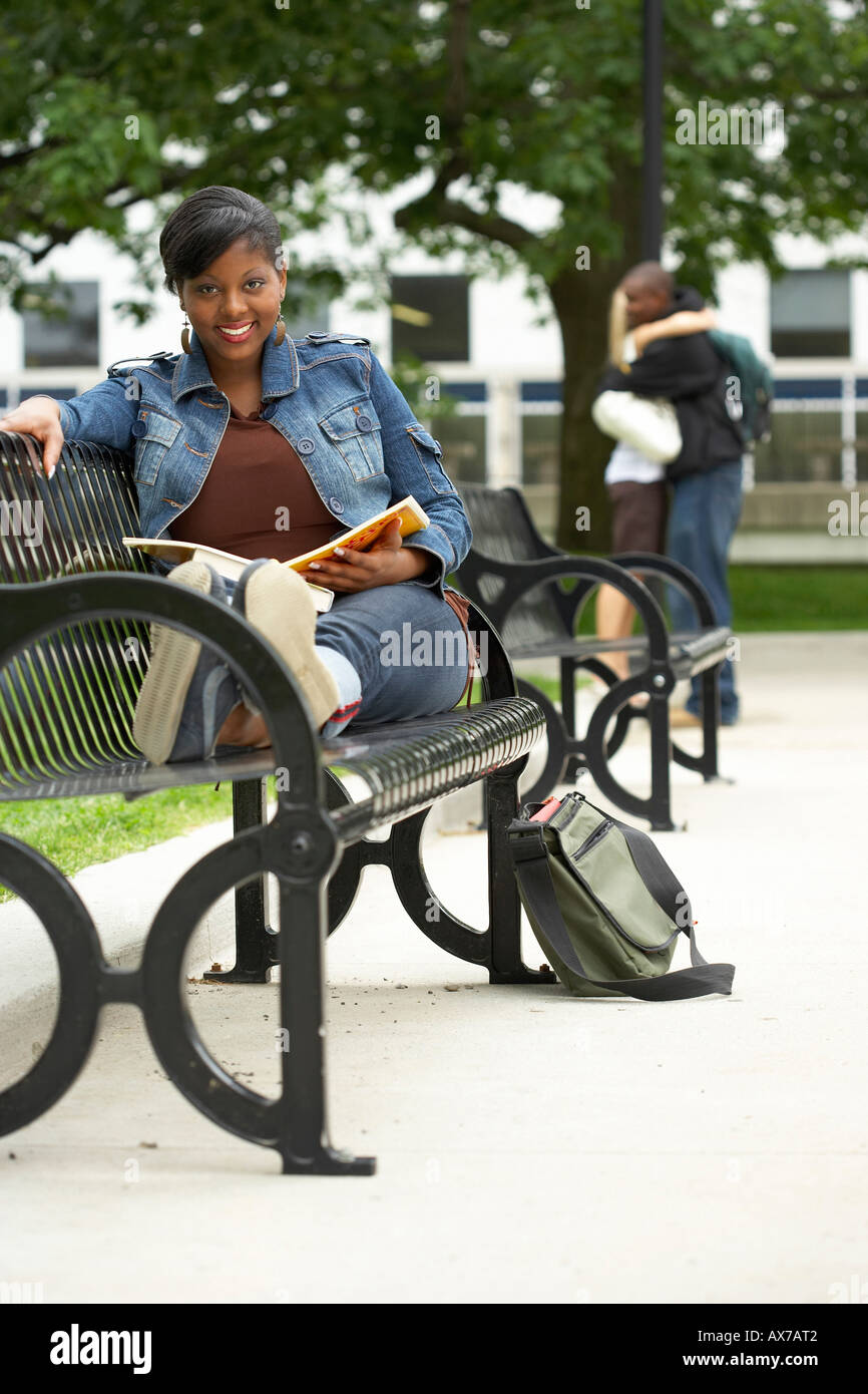 College student sitting on a bench and smiling Stock Photo - Alamy
