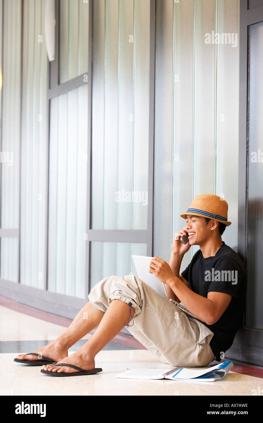 Side profile of a college student sitting in a corridor and talking on ...
