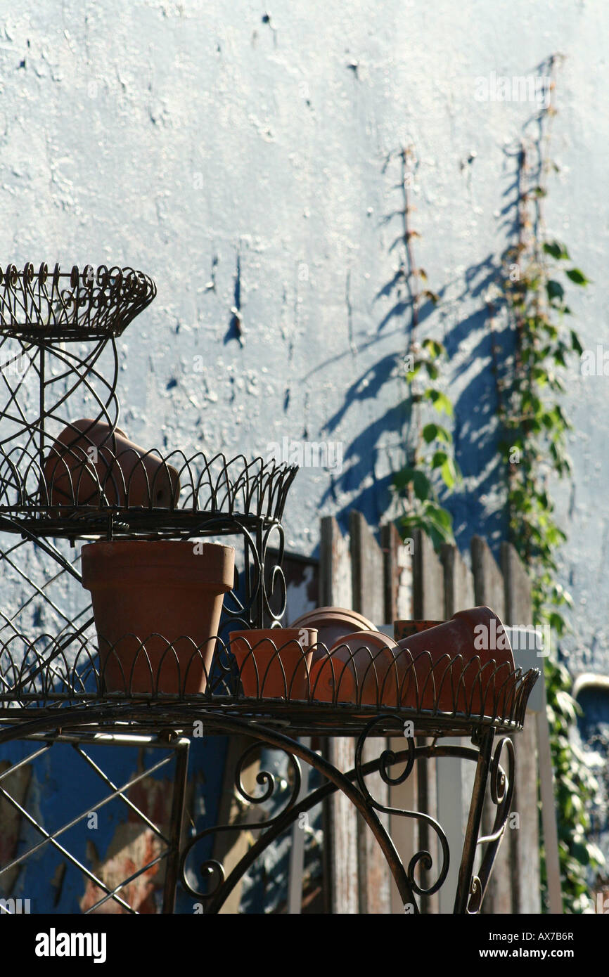 Empty flower pots sitting on a plant stand next to tall blooming ...