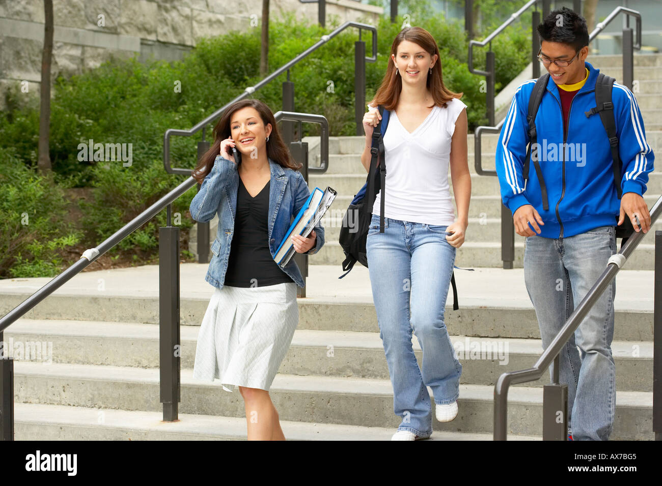 Three college students moving down a staircase Stock Photo - Alamy