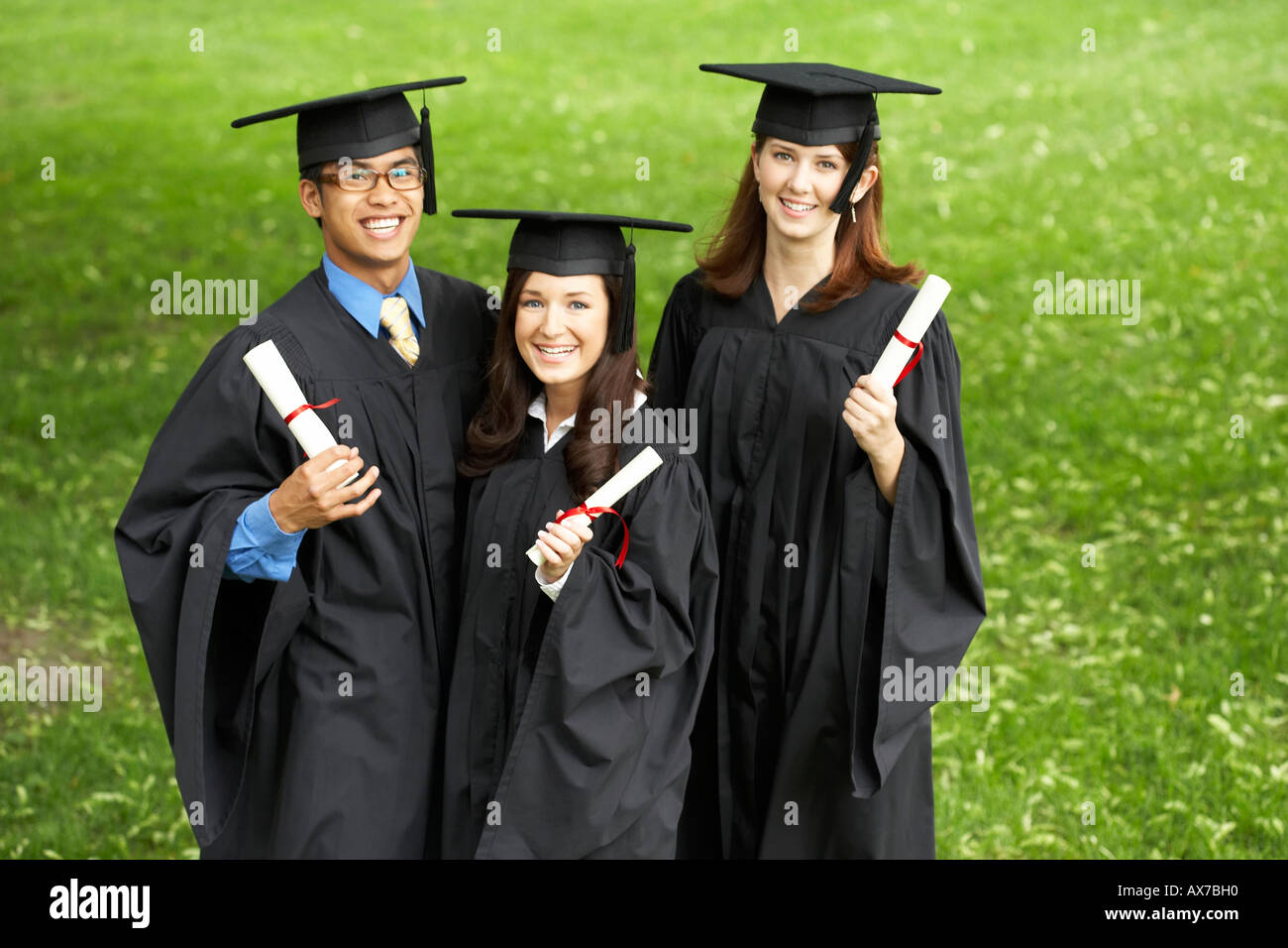 Two female graduates and a male graduate holding diplomas Stock Photo ...