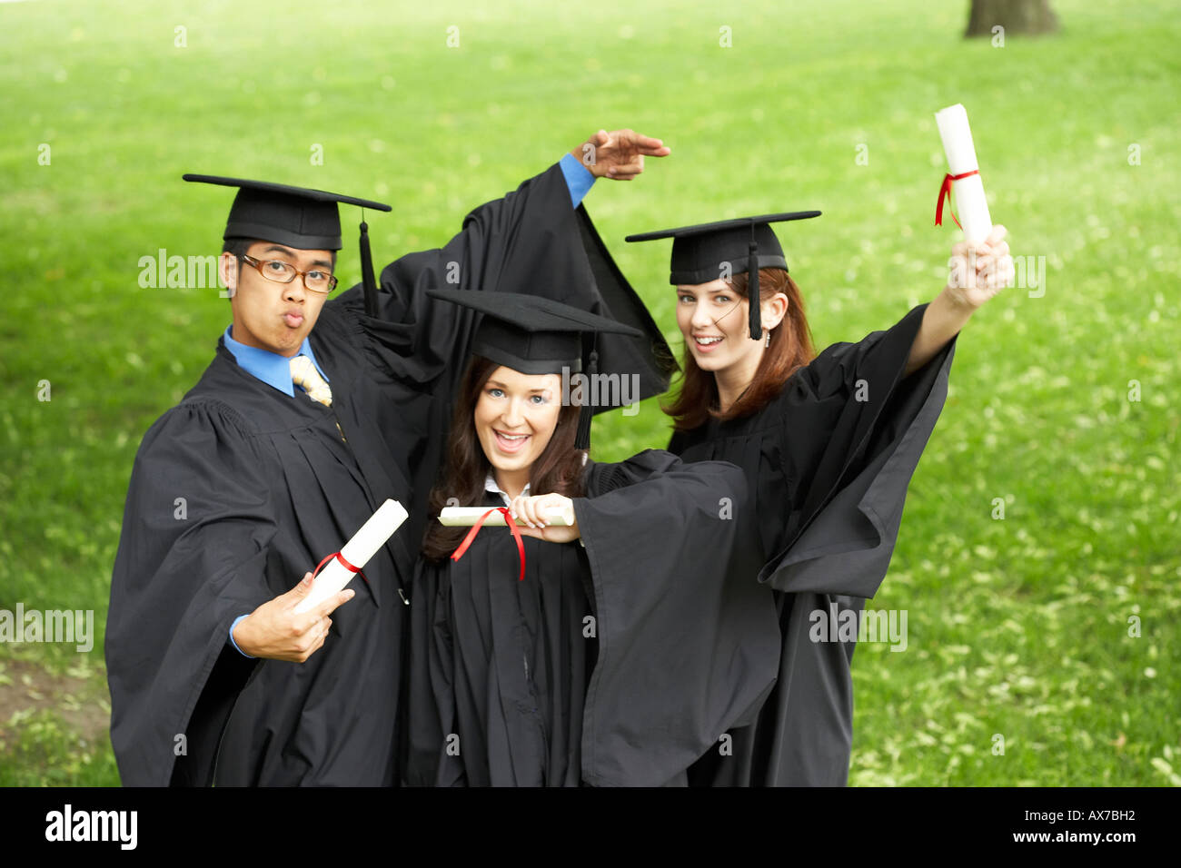 Two female graduates and a male graduate holding diplomas Stock Photo ...