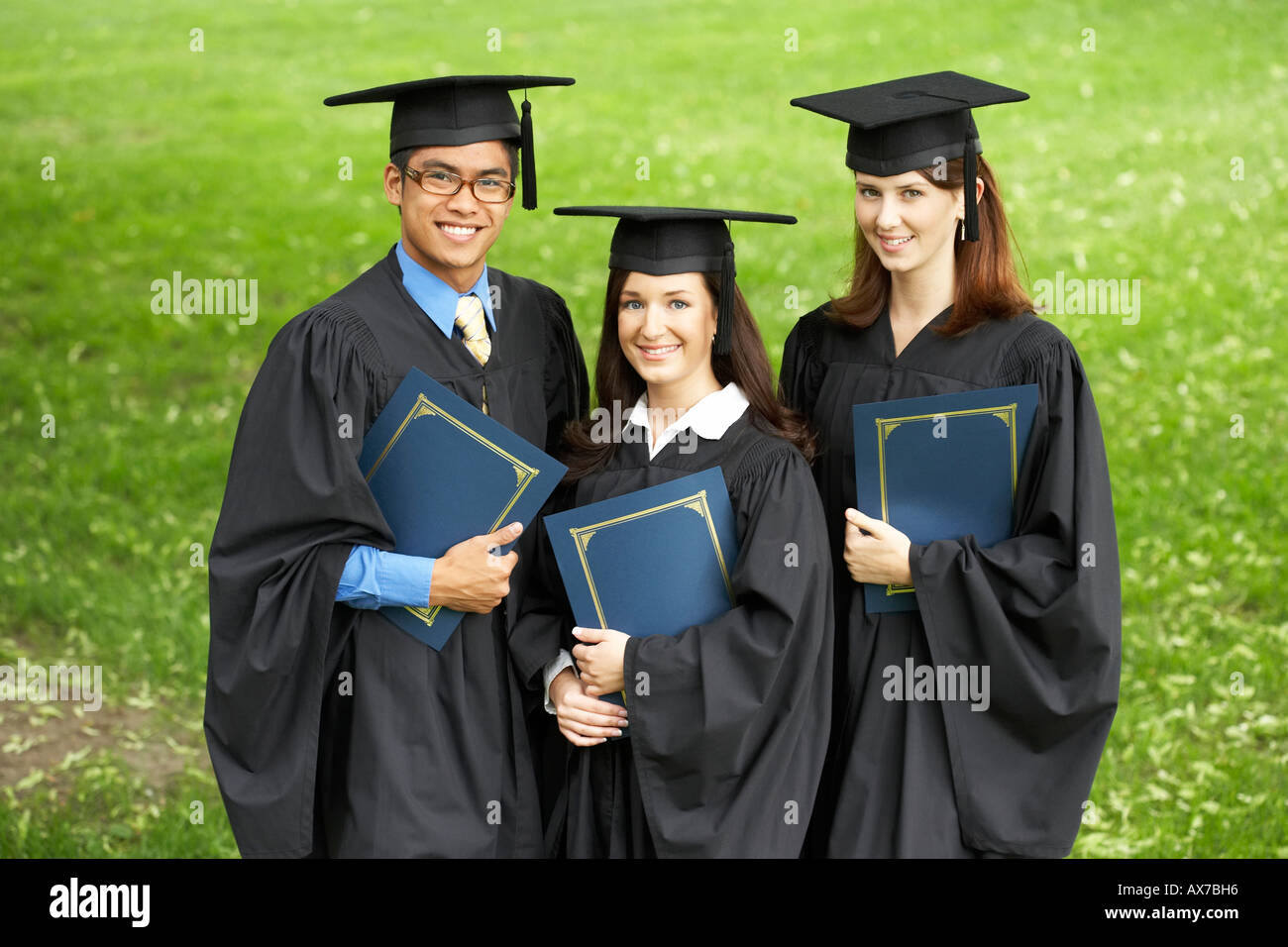 Two female graduates and a male graduate holding files Stock Photo - Alamy