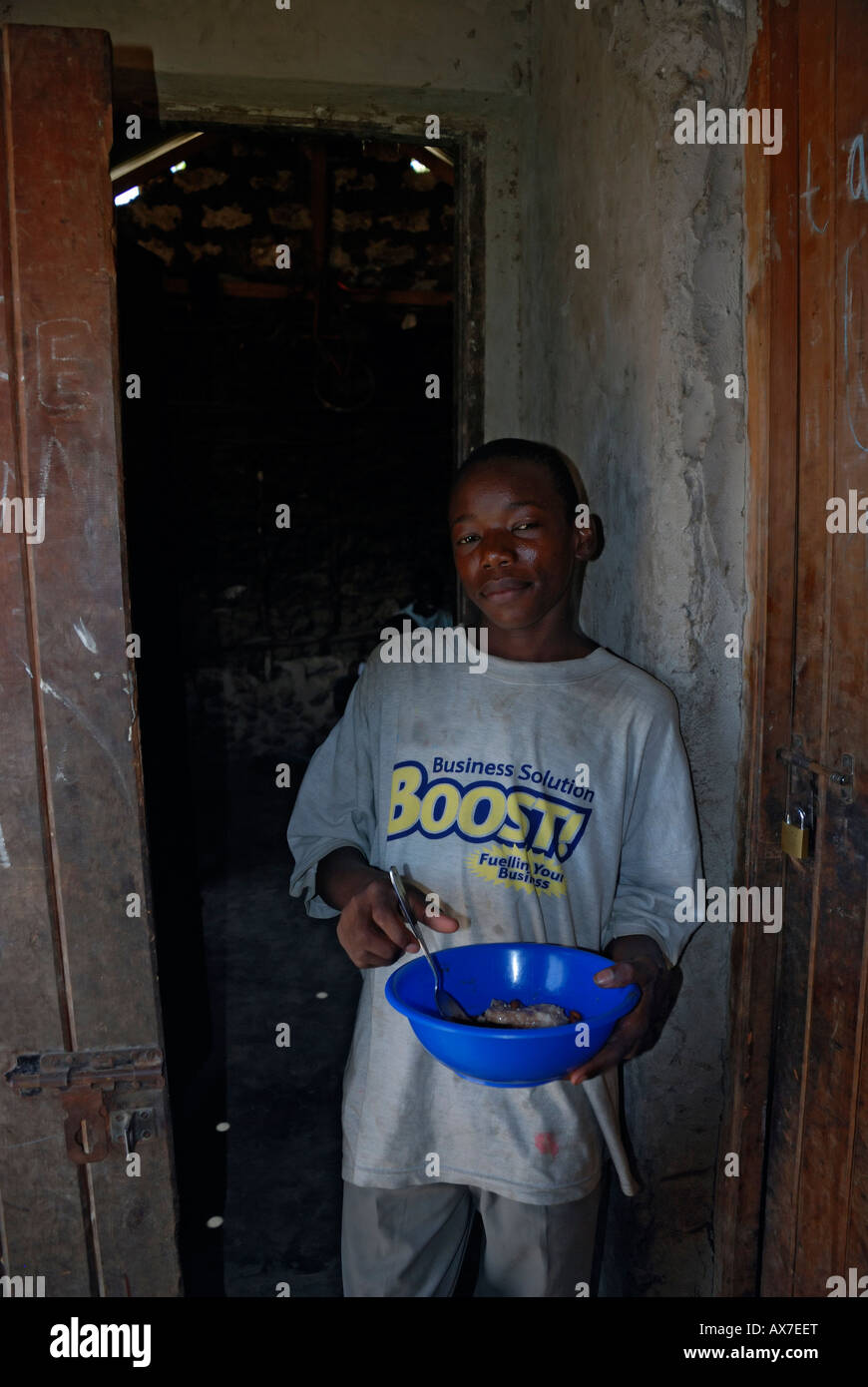 A boy stood in a doorway with his dinner plate full of beans and maize ...
