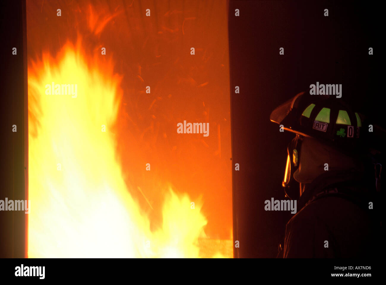 A fire fighter is peering into a room of fire before entering and ...