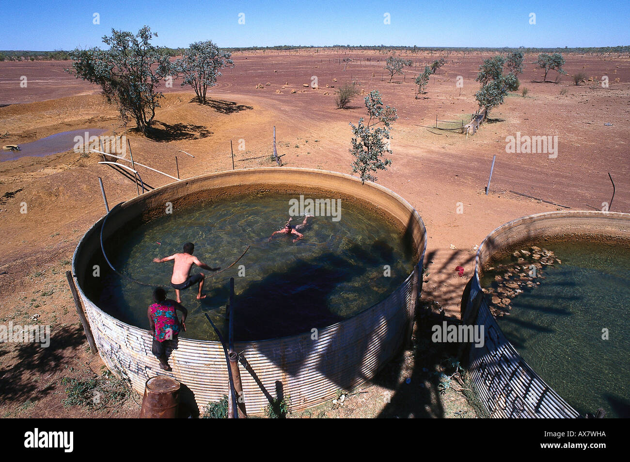 Men bathing in water reservoir for cattle, Windmill, Queensland ...