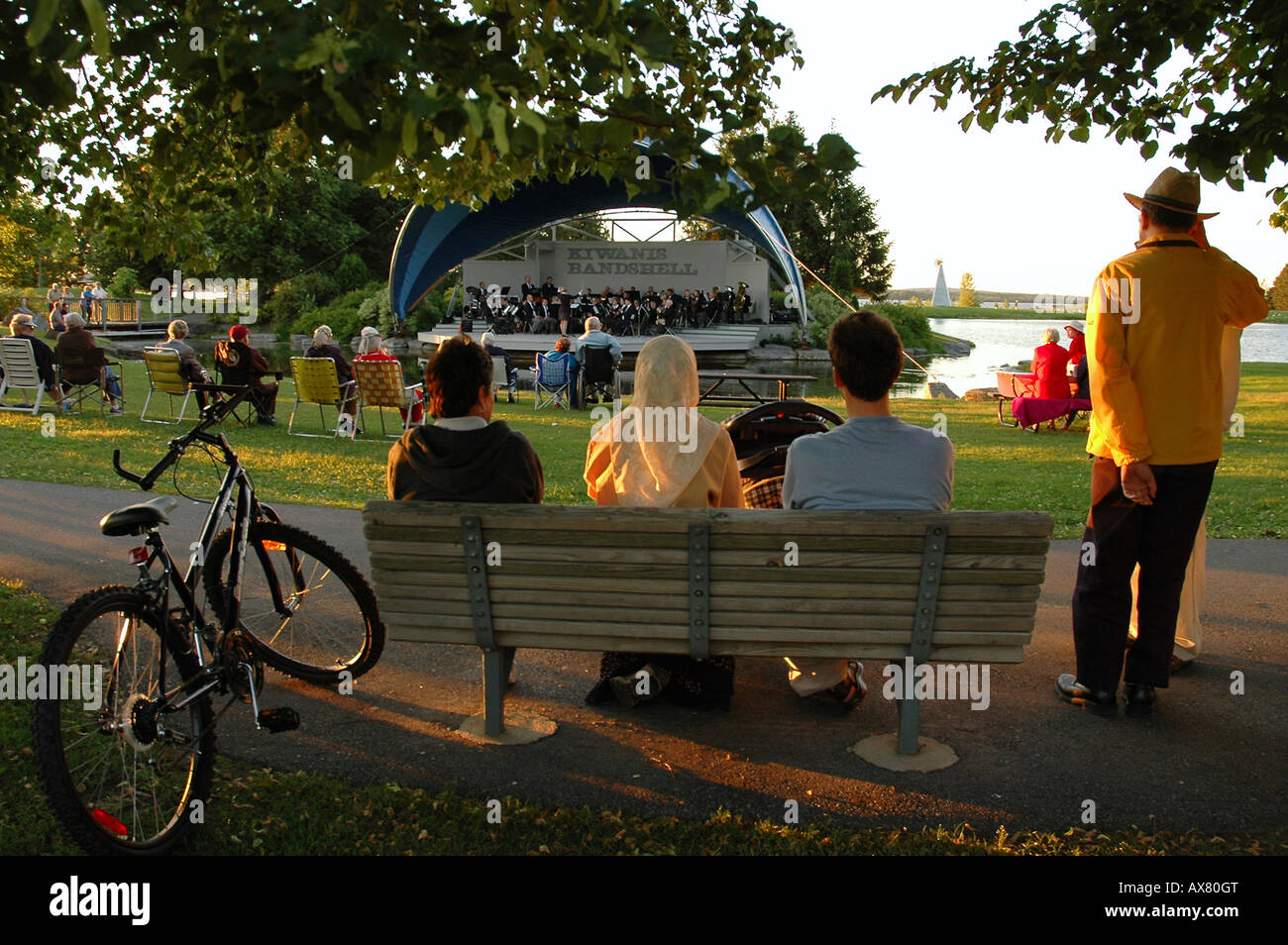 A group of people gather at a park in the evening to watch a community ...