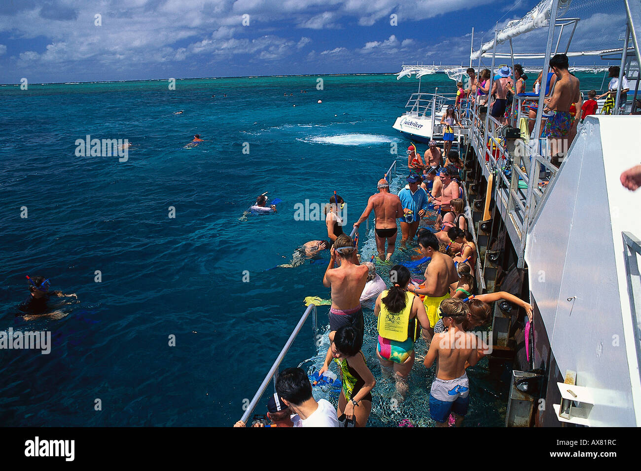 People wearing swimwear on an excursion boat and snorkeling in the sea ...