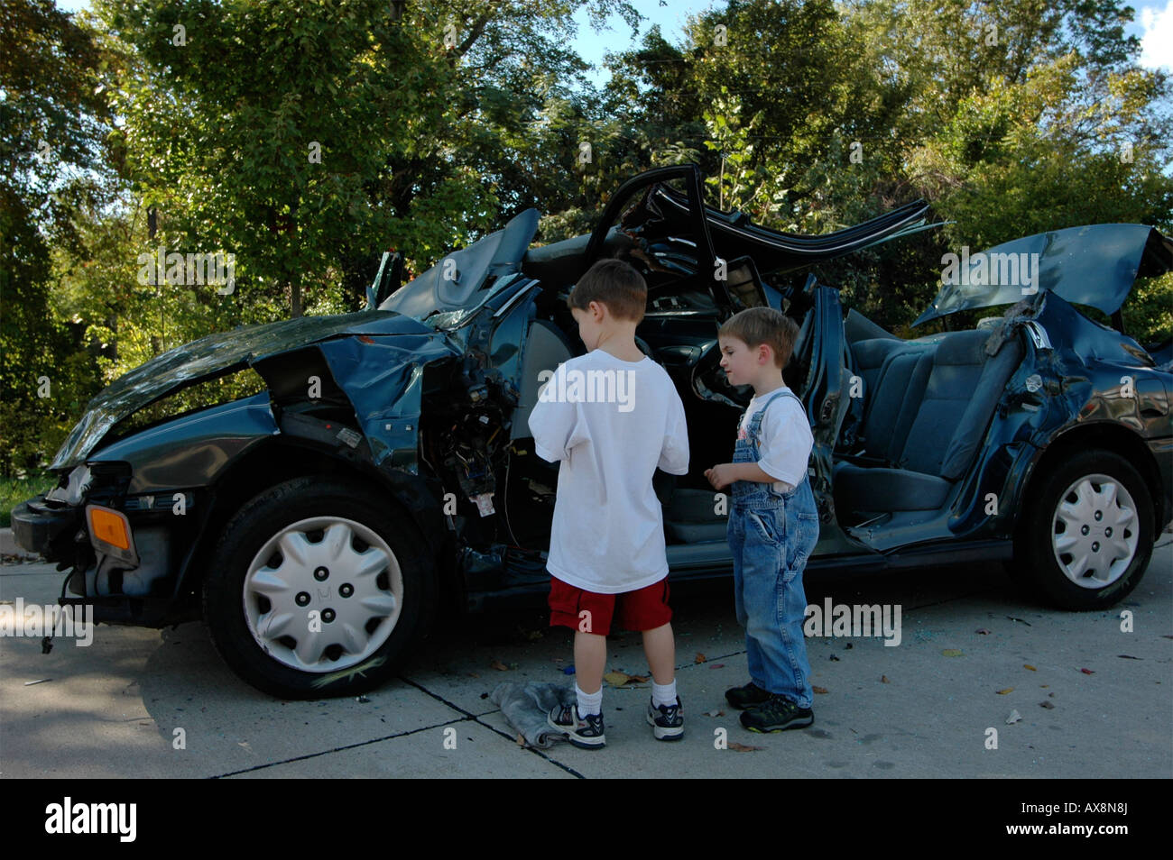 Two young boys inspecting automobile totaled in a crash Stock Photo - Alamy