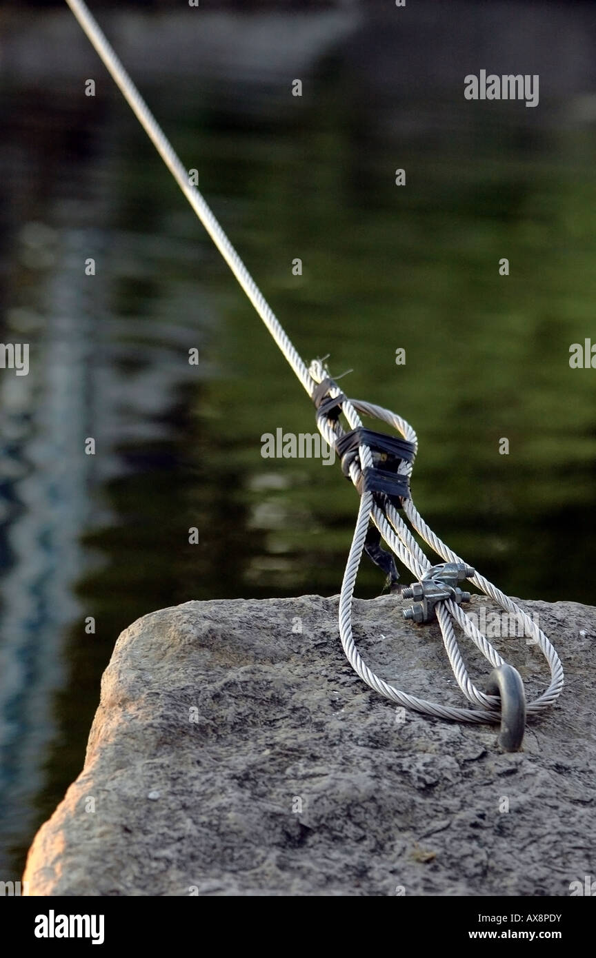 A metal support wire anchored to a large stone Stock Photo - Alamy