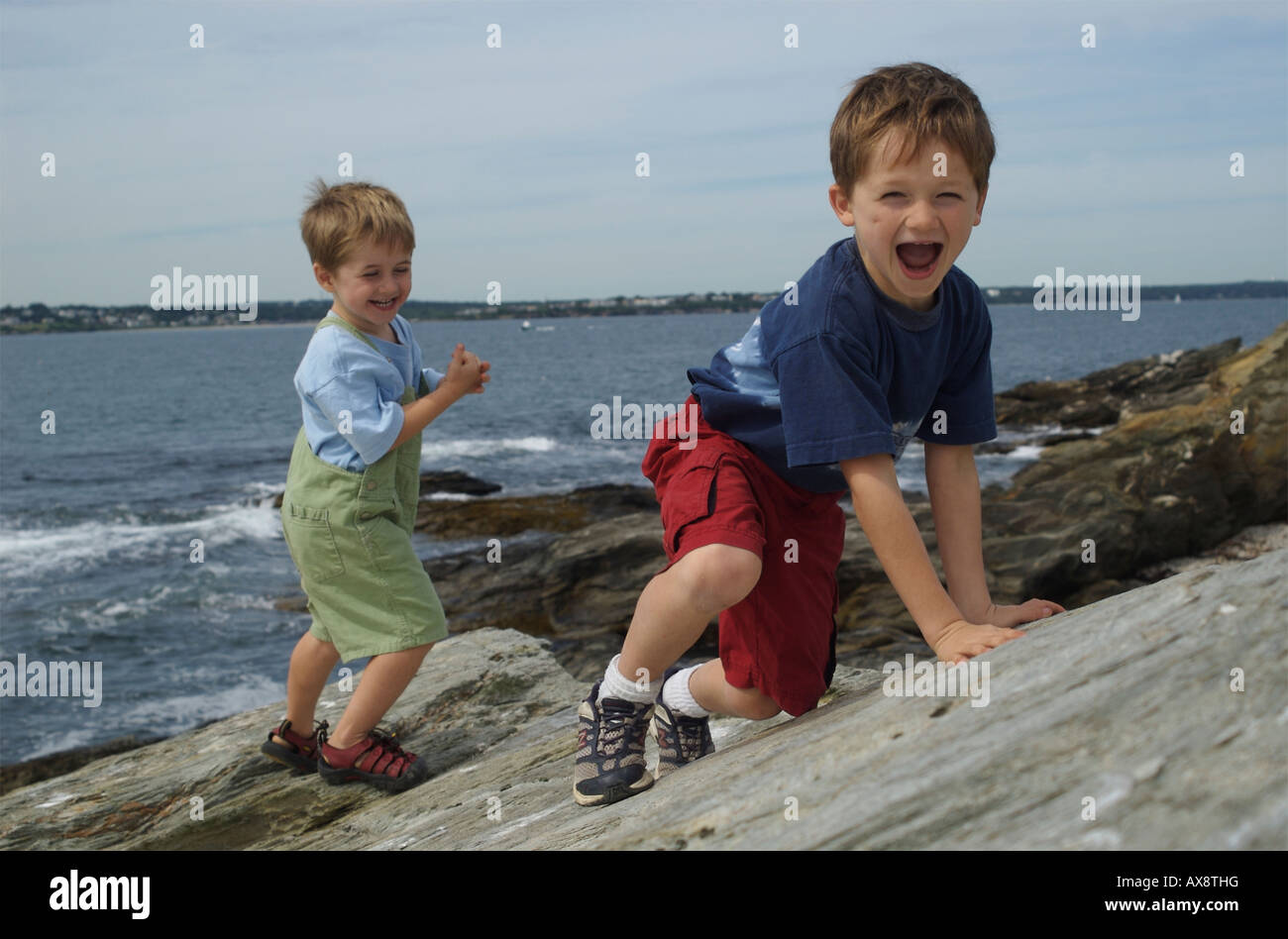 Two boys aged four and six climbing rocks and exploring the rocky ...