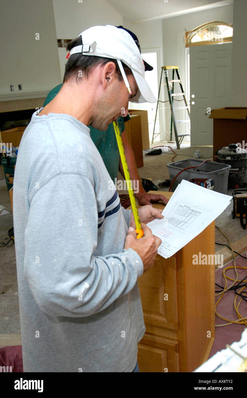 Finish carpenters install kitchen cabinets Stock Photo - Alamy