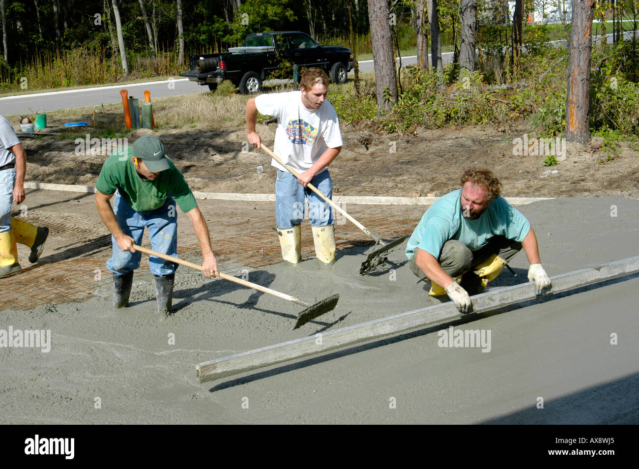 Cement Mason workers pour and finish a concrete driveway in a new home ...