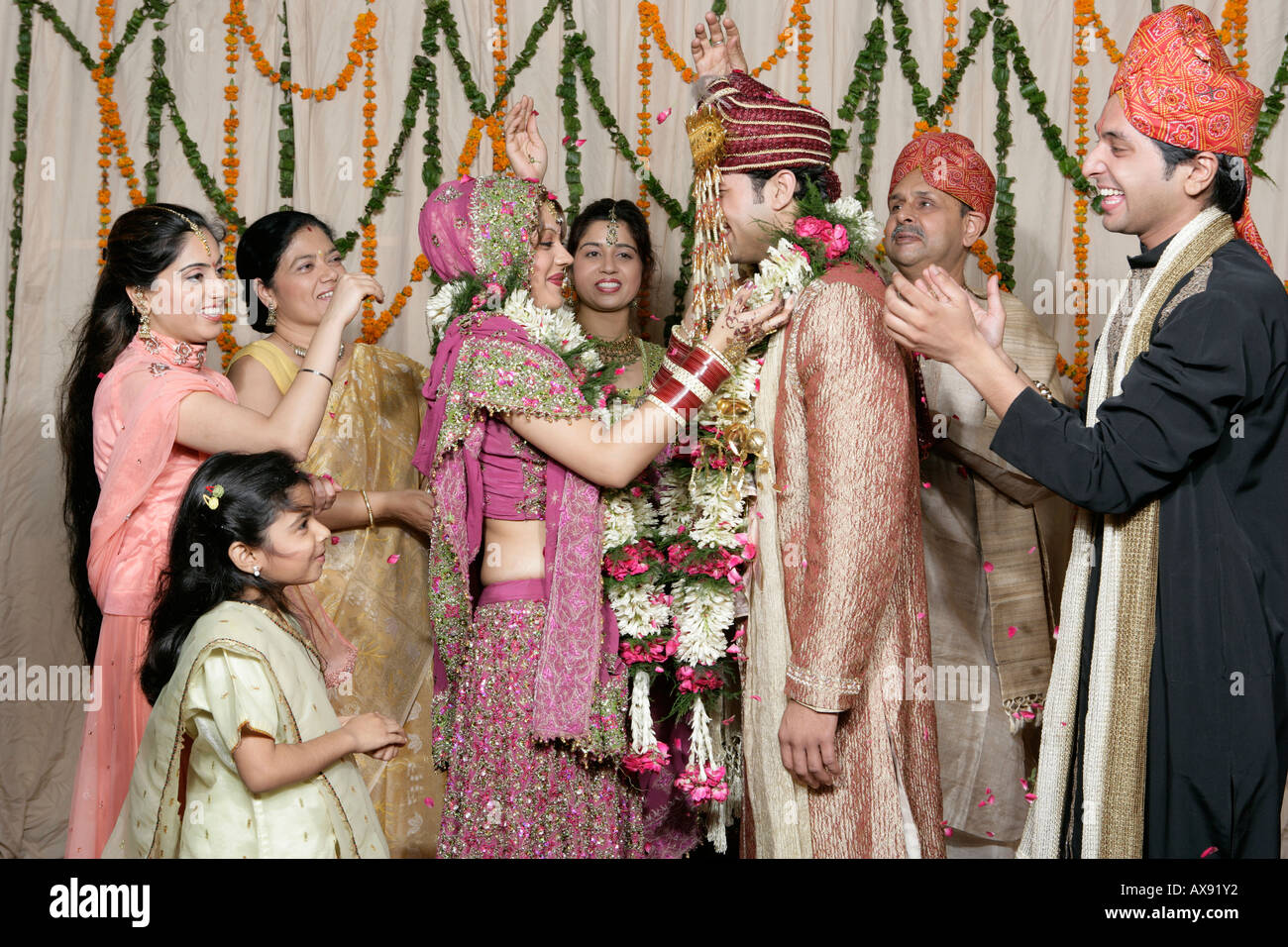 Bride and groom getting married with their relatives cheering around ...