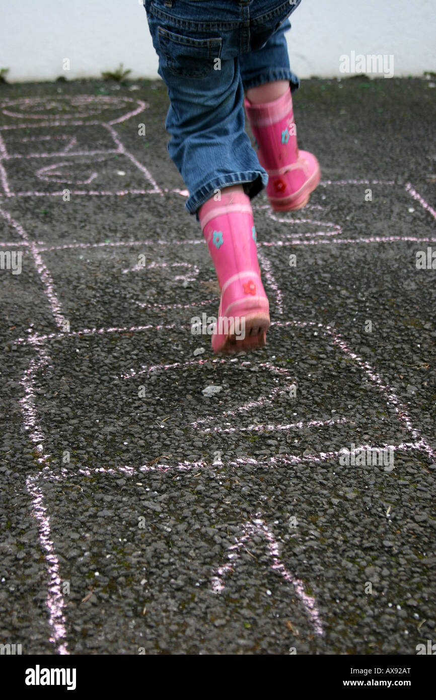 Girl jumps playing hopscotch Stock Photo - Alamy