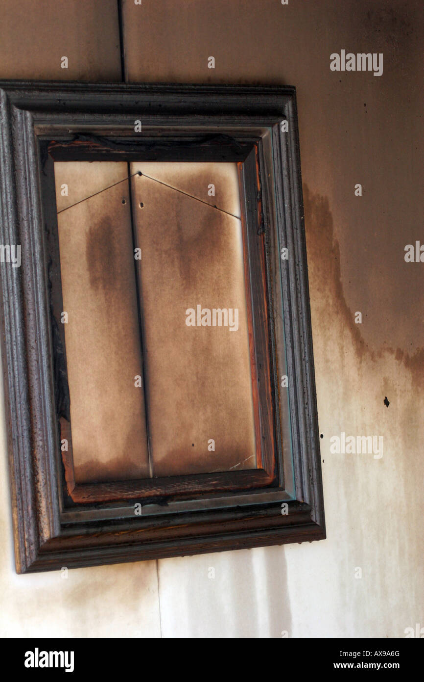 A burnt picture frame hanging on the wall in a room after a fire was ...